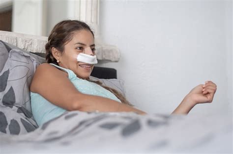 여성은 코 성형 수술 후 평상복을 입고 얼굴에 붕대를 감고 침대에 누워 결과에 대한 걱정과 불안에 떨고 있습니다 땋은 머리에 대한 스톡 사진 및 기타 이미지 Istock