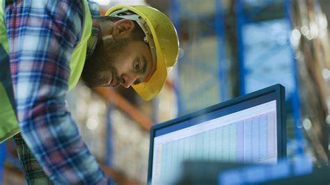 남성 관리자 하드 모자를 쓰고 그의 개인용 컴퓨터에 스프레드시트에 입력 됩니다 그는 큰 창 고 팔레트 랙 행 에입니다 창고에 대한 스톡 사진 및 기타 이미지 Istock