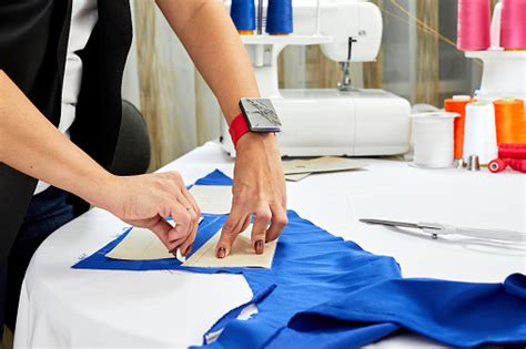 측정 테이프와 스케치로 작업하는 여성 디자이너 새로운 의류 컬렉션을 디자인 하는 워크샵에서 패션 재단사 또는 하수 드레스 메이킹 살롱에서 직물을 표시하는 여성 가위에 대한