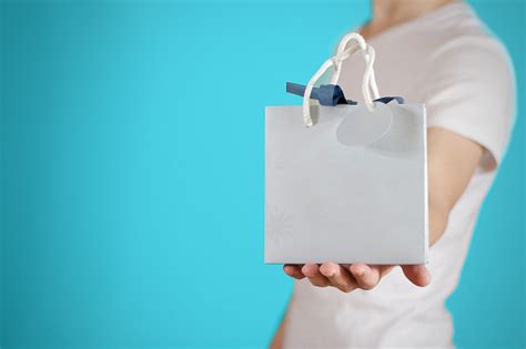 손에 들고 있는 남자는 빈 파란색 종이 선물 가방을 모의 빈 패키지 모형은 격리 된 손에 잡습니다 로고 디자인 또는 아이덴티티