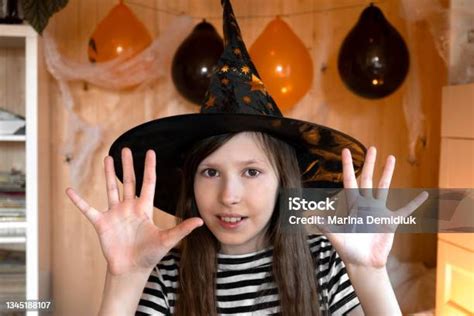 검은 마법사 모자를 쓴 작은 예쁜 소녀 마녀는 무서운 제스처로 부를 말한다 할로윈 아이 초상화 집에서 할로윈 의상을 입은 소녀