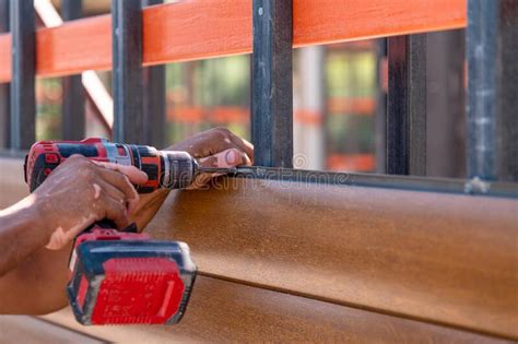 Man Assembling Composite Wall Siding Using Cordless Screwdriver Stock Man Assembling Composite Wall Siding Using Cordless Screwdriver Stock