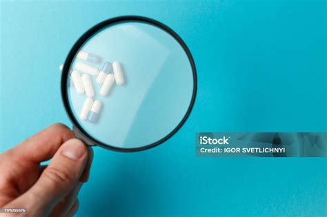 파란색 배경에 돋보기 아래 제약 의약품 알약 정제 및 캡슐을 모듬 맨 위 보기 플랫 레이 공간을 복사합니다 의학 개념 파스텔