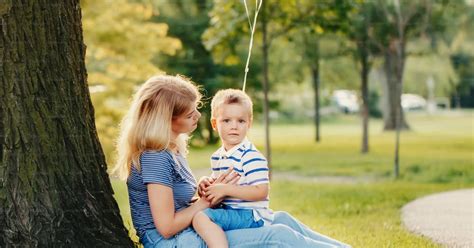 젊은 백인 어머니와 소년 유아 아들은 공원에서 푸른 잔디에 함께 앉아 있습니다 가족 엄마와 아이는 여름날 야외에서 의사 소통을합니다 행복 한 정통 가족 어린 시절 생활
