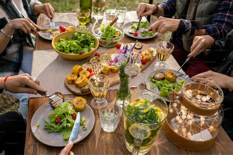 나이프와 포크를 들고 구운 야채와 샐러드를 먹는 여러 친구들의 손 사진 Unsplash의 사람 이미지