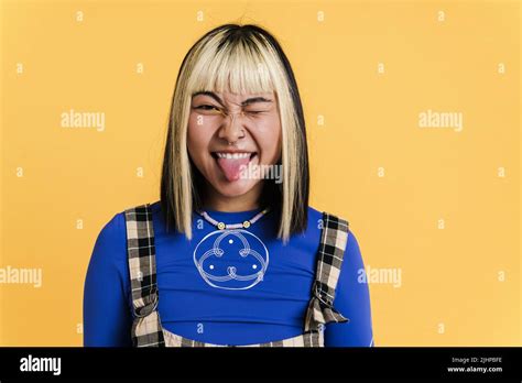 Asian Girl With Piercing Showing Her Tongue And Winking Isolated Over
