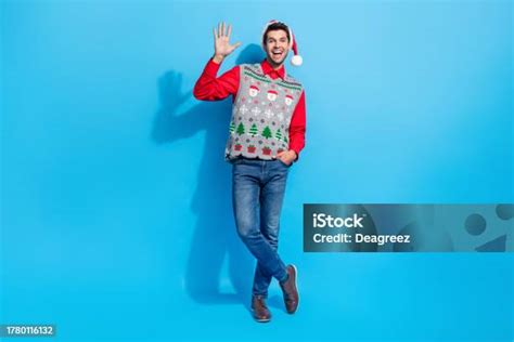 좋은 기분 긍정적 인 남자의 전체 길이 사진 입고 크리스마스 모자 인쇄 양복 조끼 흔들고 손바닥 말한다 안녕 파란색 배경에 고립 된 12월에 대한 스톡 사진 및 기타 이미지