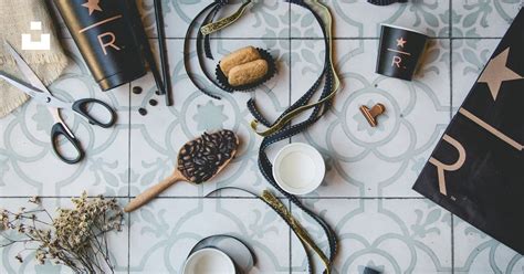 회색 타일에 커피 원두와 컵 근처의 갈색 및 검은색 스트랩 사진 Unsplash의 무료 플랫레이 이미지