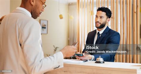 호텔 신용 카드 및 손님 Pos 및 환대를 위한 친절한 리셉션 서비스와 함께 데스크에 있는 남자 체크인 지불 및 접수 담당자는