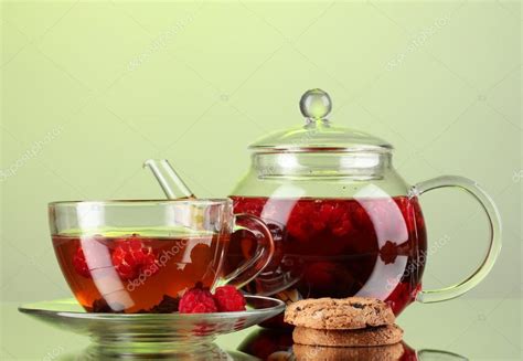 Black Fruit Raspberry Tea In Glass Teapot And Cup On Green Background