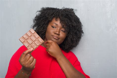 먹는 초콜릿 바 심각한 회색 그런 지 벽에 젊은 아프리카계 미국인 여자 얼굴 아주 혼란 스 러 워 아이디어 질문에 대 한 생각 개념에 대한 스톡 사진 및 기타 이미지