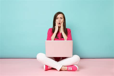 핑크 블루 파스텔 벽 배경 스튜디오에 고립 된 노트북 Pc를 사용 하 여 바닥에 앉아 장미 셔츠 블라우스 흰색 바지에 젊은 여자의 전체 길이 초상화 패션 라이프 스타일