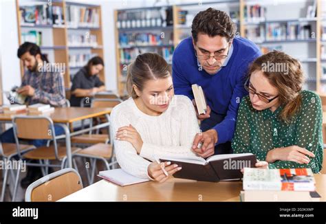 Female Babes Working With Professor In Library Stock Photo Alamy