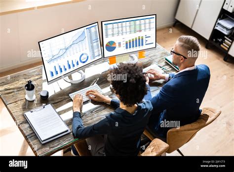 Side View Of Male And Female Stock Market Broker Analyzing Graphs On
