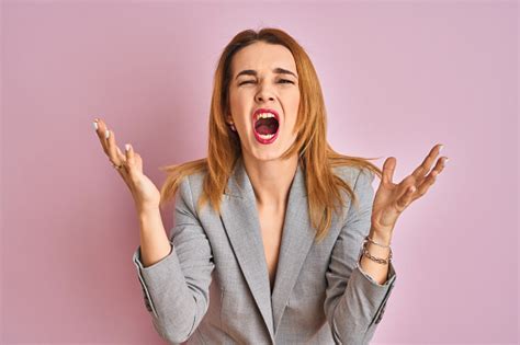 고립 된 분홍색 배경 위에 양복을 입은 젊은 백인 비즈니스 여성은 공격적인 표정과 팔을 들고 미친 소리와 고함을 지으며 좌절 개념입니다 감정에 대한 스톡 사진 및 기타