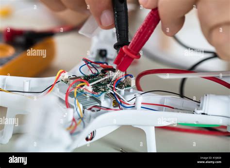 Close Up Of A Man Testing Electric Current Of Disassembled Drone Using Multimeter Tool Stock