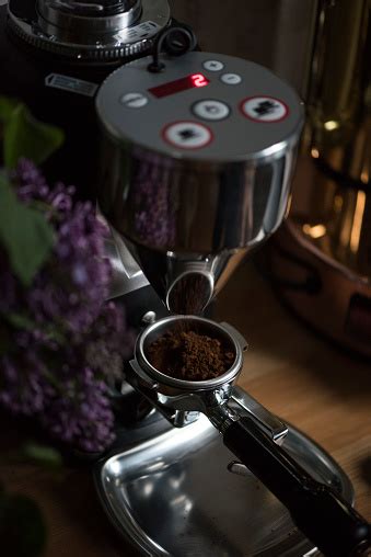 커피 분쇄기에 분쇄 신선한 커피 원두를 Portafilter로 남자 백그라운드에서 몇 가지 꽃 라일락 바리 테이블 개화기에 대한