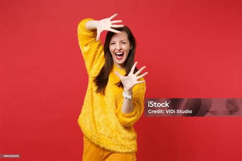 노란 털 스웨터 표시에 재미 있는 웃음 젊은 여자의 초상화 스튜디오에서 밝은 빨간색 배경에 고립 확산 손가락 손바닥 사람들이