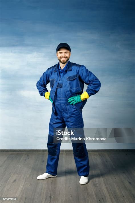 엄지 손가락 파란 작업 복을 입은 젊은 잘생긴 남자가 파란 배경에 고립 된 미소를 짓고 엄지 손가락을 위로 합니다 엄지손가락을