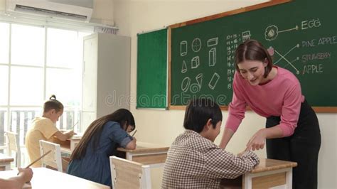 Teacher Checking Cute Student Homework While Explaining Idea At Class