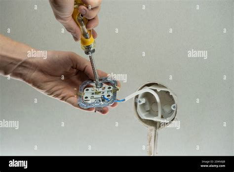 A Man Installs An Electrical Outlet In The Wall Installation Wire Into A Plug Close Up Of