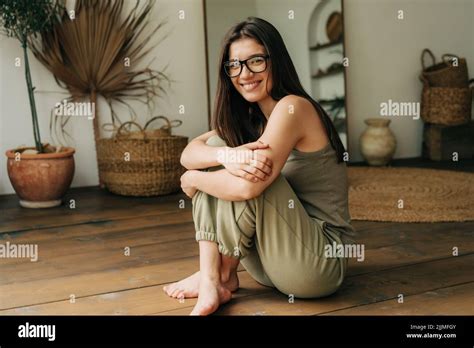 Une Jeune Fille Brune De Vingt Ans En Lunettes Est Assise à Pattes