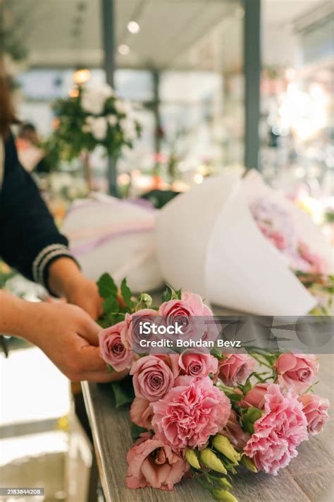 분홍색과 파스텔 톤의 꽃다발을 나무 카운터에 배치한 플로리스트는 흐릿한 꽃집을 배경으로 하고 있습니다 꽃꽂이와 자연의 아름다움의