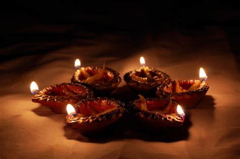 인도 의 전통 디야 또는 빛나는 불꽃이있는 점토 오일 램프는 디왈리 의 인도 힌두교 문화 축제를 축하하는 동안 동그라미로 유지되었습니다 어두운 배경 공간 배경을 복사합니다