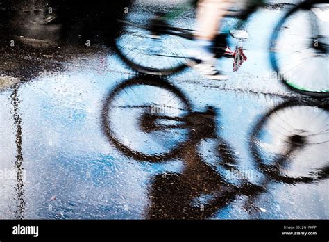 Cyclist Passing By Reflected On Rain Wet Road Berlin Germany Stock Photo Alamy