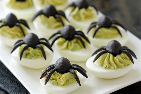 Spider Avocado Deviled Eggs On A Halloween Themed Tray With Black Olive