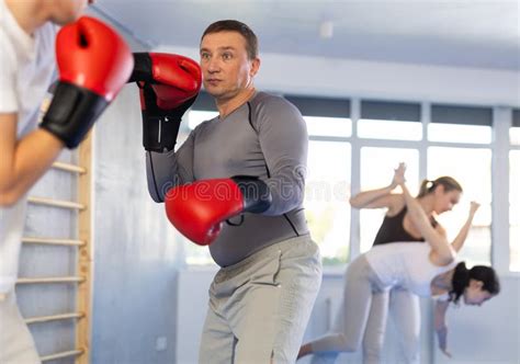 Two Boxers In Sportswear Are Engaged In Boxing Sparring In Gym Stock