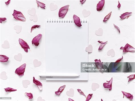 오픈 블랭크 노트북 펜 모란 꽃잎 하트 모양의 색종이가 질감이 있는 배경에 있습니다 발렌타인 데이에 대한 꽃 레이아웃 플랫 레이 맨 위 보기입니다 공간을 복사합니다 메모장에