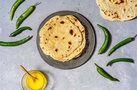 Homemade Indian Chapati Or Roti On Grey Concrete Background With Human Hand Pouring Butter Ghee
