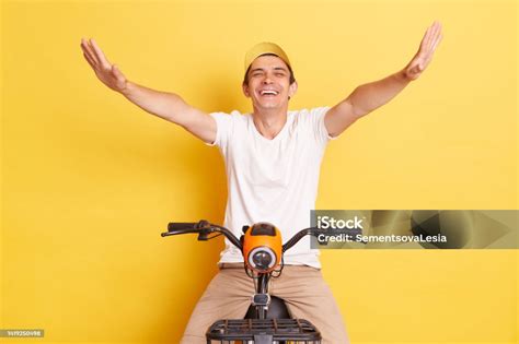 하얀 티셔츠와 모자를 쓰고 전기 자전거를 타고 노란 배경에 고립 된 여가 시간을 즐기는 매우 행복한 백인 청년 35 39세에 대한 스톡 사진 및 기타 이미지 Istock