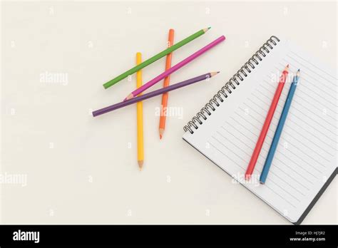 Ready To Write Spiral Bound Lined Note Pad With Coloring Pencils Lying On A White Desk Stock
