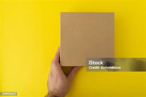 노란색 배경에 손에 사각형 골판지 상자 공간을 복사합니다 모의 갈색에 대한 스톡 사진 및 기타 이미지 갈색 노랑 배경 주제 Istock