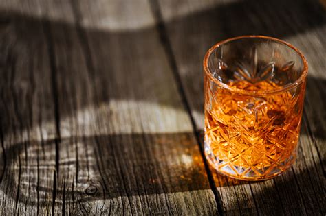 소박한 나무 테이블 위의 유리잔에 얼음이나 브랜디를 곁들인 위스키 유리잔에 얼음을 넣은 위스키 유리에 위스키 또는 코냑 선택적 초점 스톡 사진 0명에 대한 스톡 사진 및