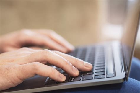 Premium Photo In A Closeup A Mans Hands Can Be Seen Typing On A Modern Laptop Keyboard With