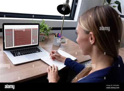 Une Femme Du Caucase Se Trouve Sur Un Ordinateur Portable Avec Codage à Lécran Prise De Notes