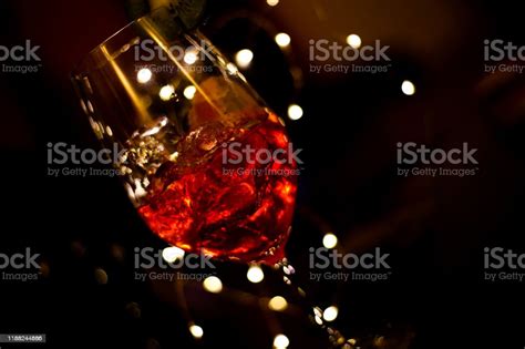얼음 조각과 고립 된 빨간 칵테일 유리의 닫습니다 전기 조명에서 다채로운 활기찬 보케와 검은 배경입니다 0명에 대한 스톡 사진