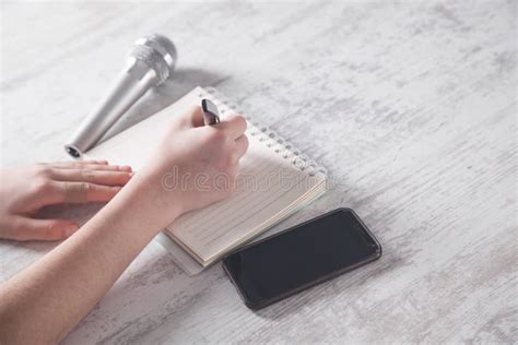 Girl Writing On Notepad Microphone And Smartphone On The Desk Stock