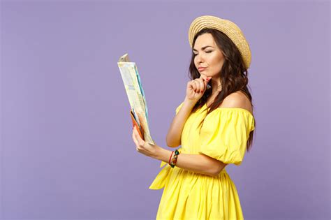 노란 드레스에 잠겨있는 젊은 여자 여름 모자 개최 도시 지도 파스텔 바이올렛 벽 배경에 고립 된 여권 탑승권 티켓 사람들은 진심으로 감정 라이프 스타일 개념입니다 복사