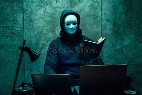anonymous hacker wearing face mask working on computer in dark room