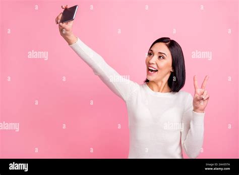 Photo Of Amazing Lady Holding Telephone In Hands Making Selfies Showing V Sign Symbol Wear White
