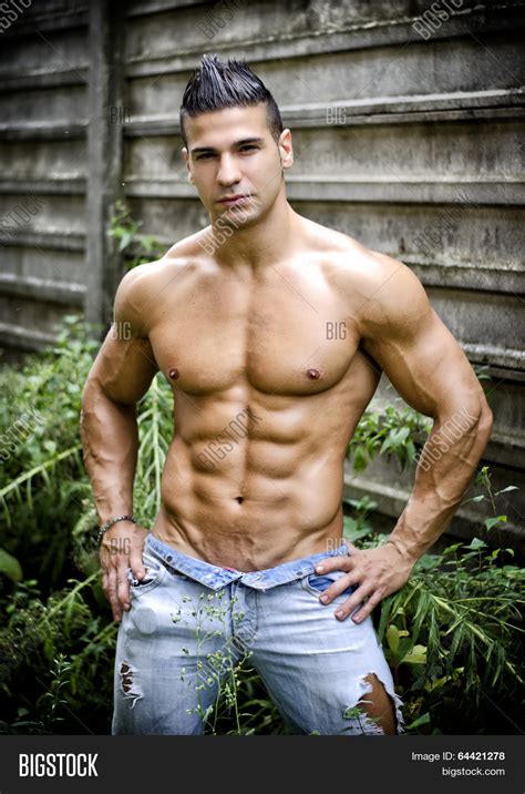 Muscular Young Latino Man Shirtless In Jeans In Front Of Concrete Wall