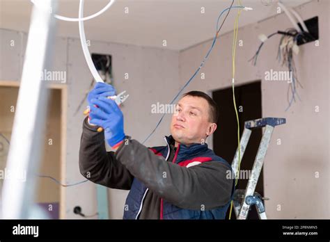 Experienced Friendly Electrician Laying Electric Wires In Building Under Construction Stock