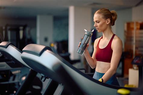 체육관의 러닝머신에서 운동하는 동안 물을 마시는 운동선수 여성 체육관에 대한 스톡 사진 및 기타 이미지 체육관 헬스 클럽 사람들 Istock