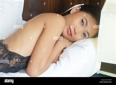 Beautiful Asian Woman Posing Wearing Black Lingerie On A Bed With White