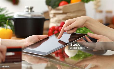 태블릿 또는 터치 패드를 사용 하 여 인간의 손의 클로즈업 부엌에 두 여자입니다 요리 우정 또는 온라인 쇼핑 개념 가까운에 대한