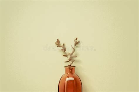 Brown Glass Vase Of Dry Eucalyptus Leaf And Yellow Wall Background